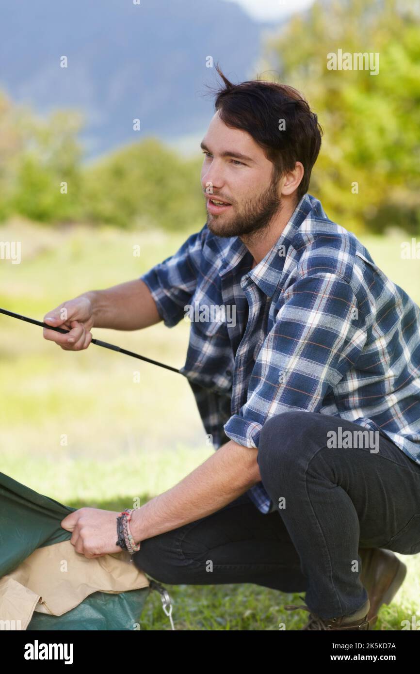 Putting up a tent is childs play for him. Young man putting up a ...