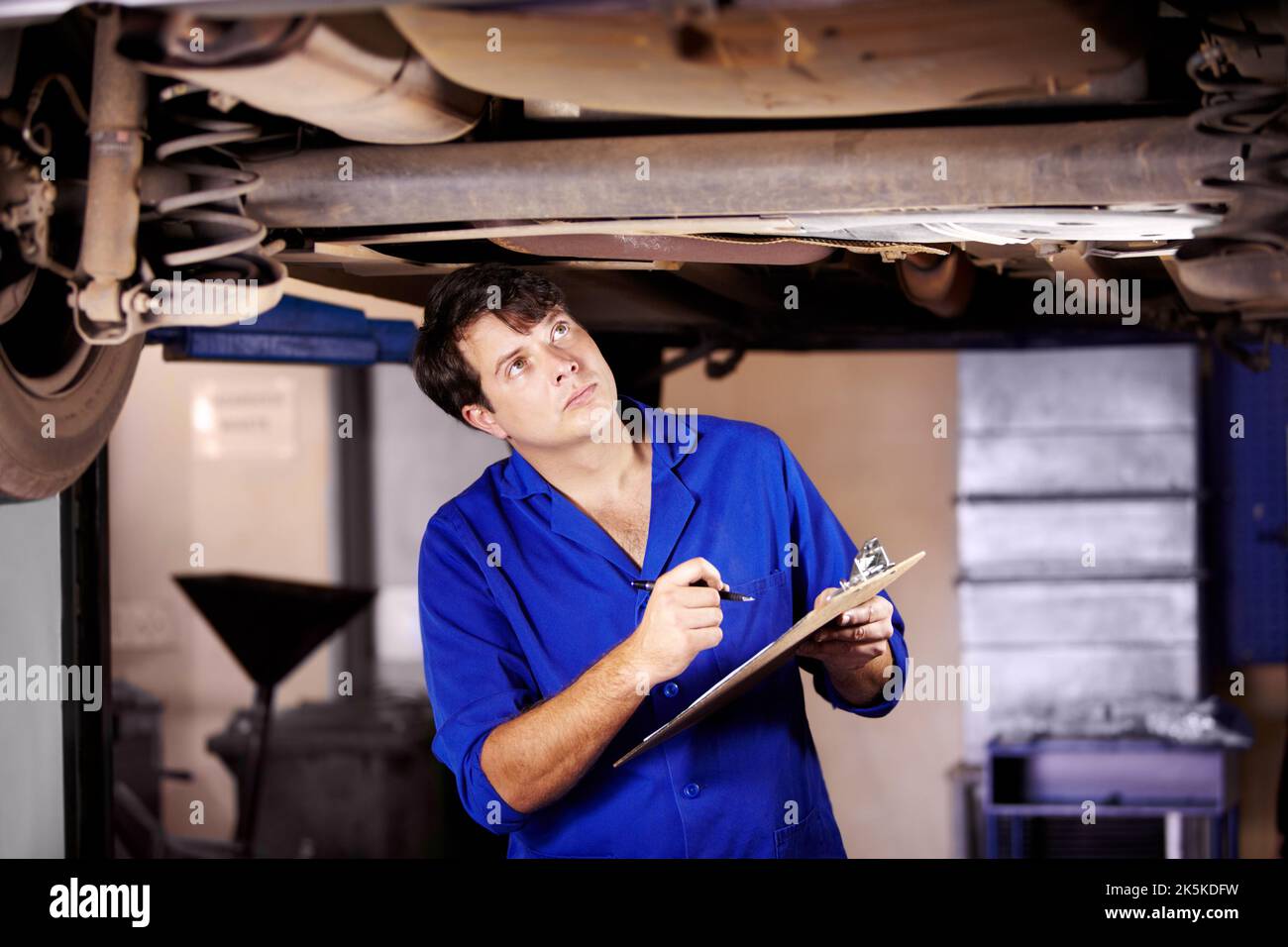 Checking the underneath of the car. A young male mechanic looking at ...