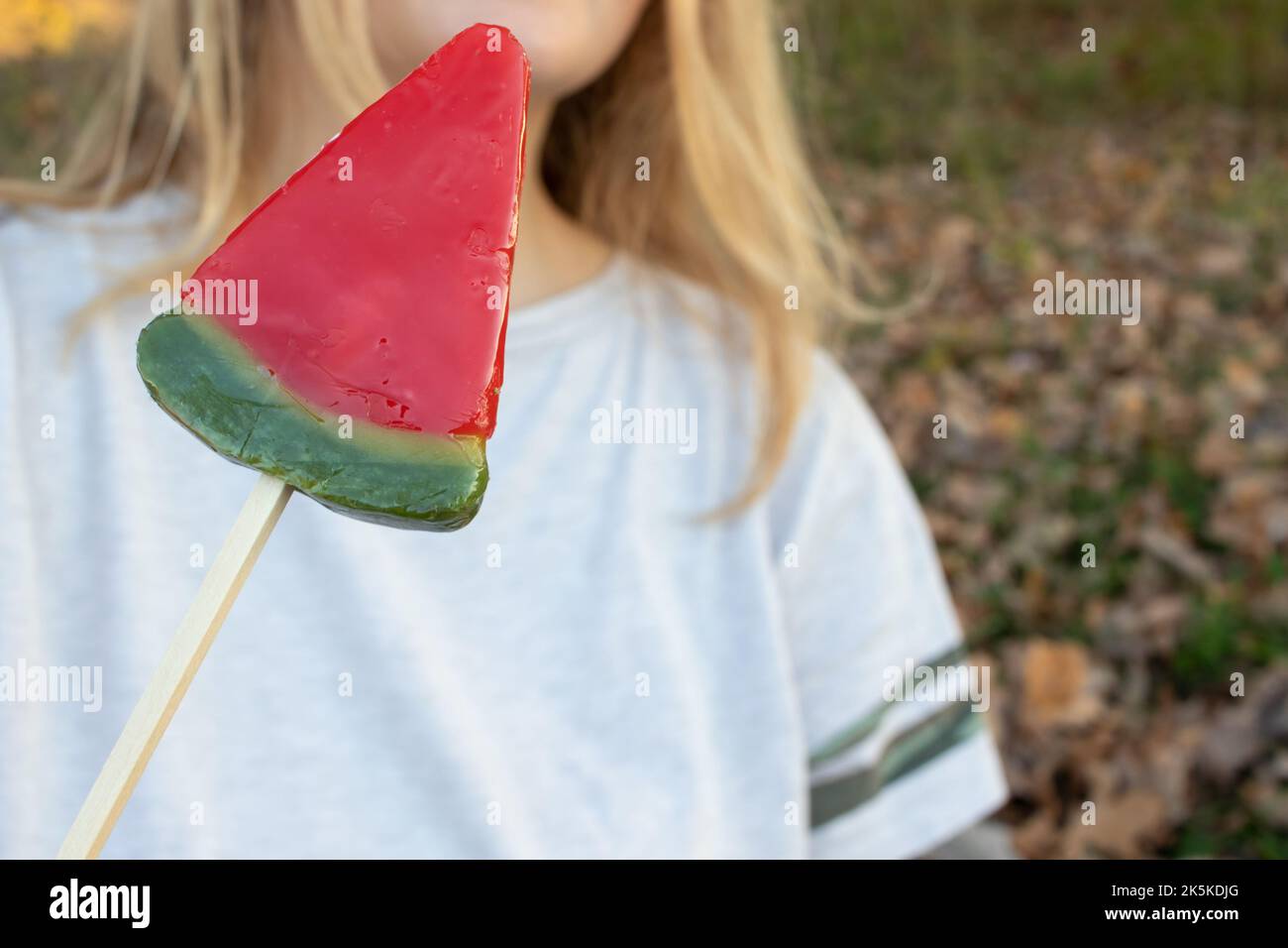 Girl eating a lollipop. Young woman holding a red candy watermelon ...