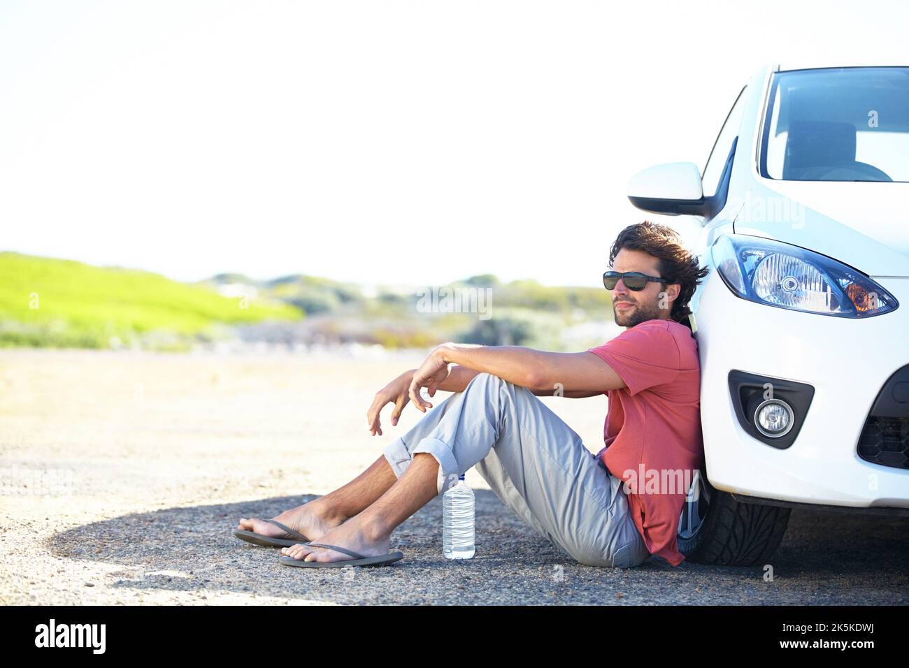 Waiting for roadside assistance. A young man sitting on the road ...