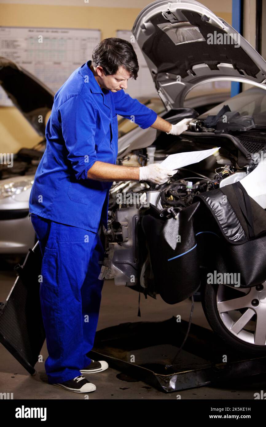 These numbers make no sense. A male mechanic reading some papers while ...