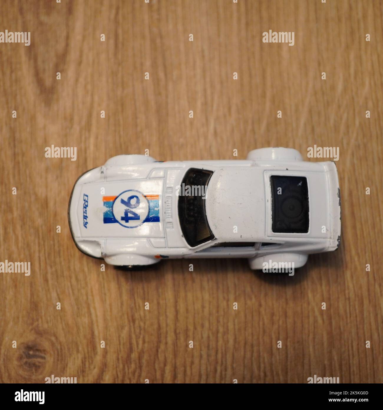 A top view of a white Mattel Hot Wheels toy car on a wooden surface ...