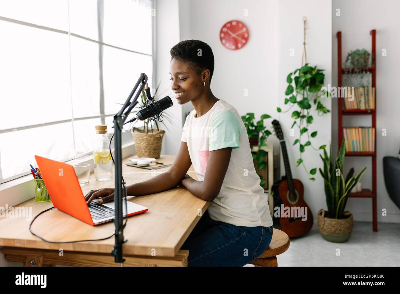 Smiling young podcaster woman recording radio podcast from modern home ...