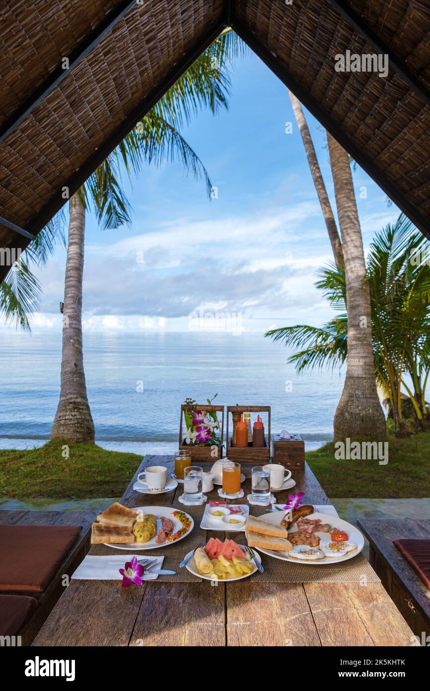 breakfast table on the beach with palm trees in Thailand. colorful ...