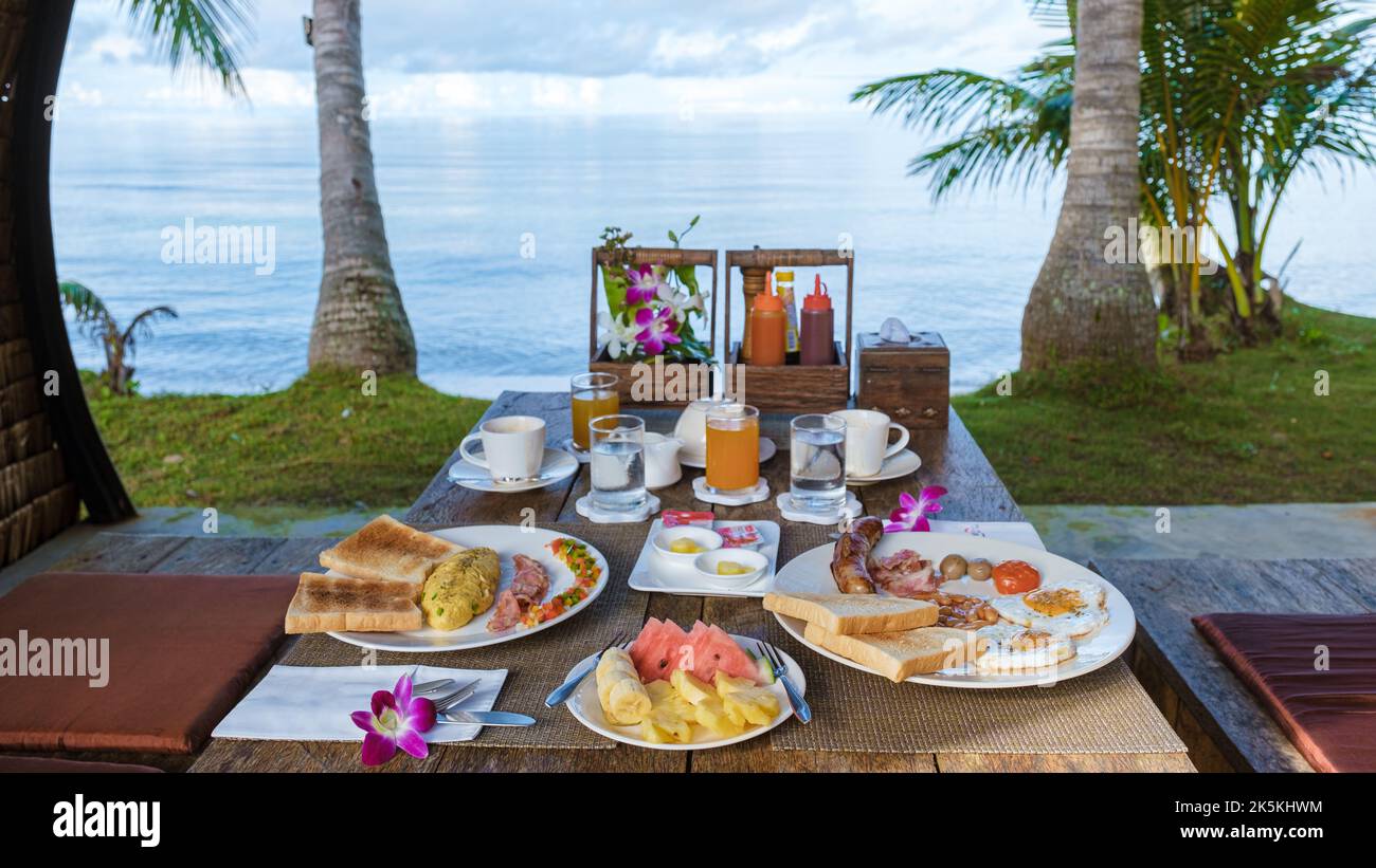 breakfast table on the beach with palm trees in Thailand. colorful ...