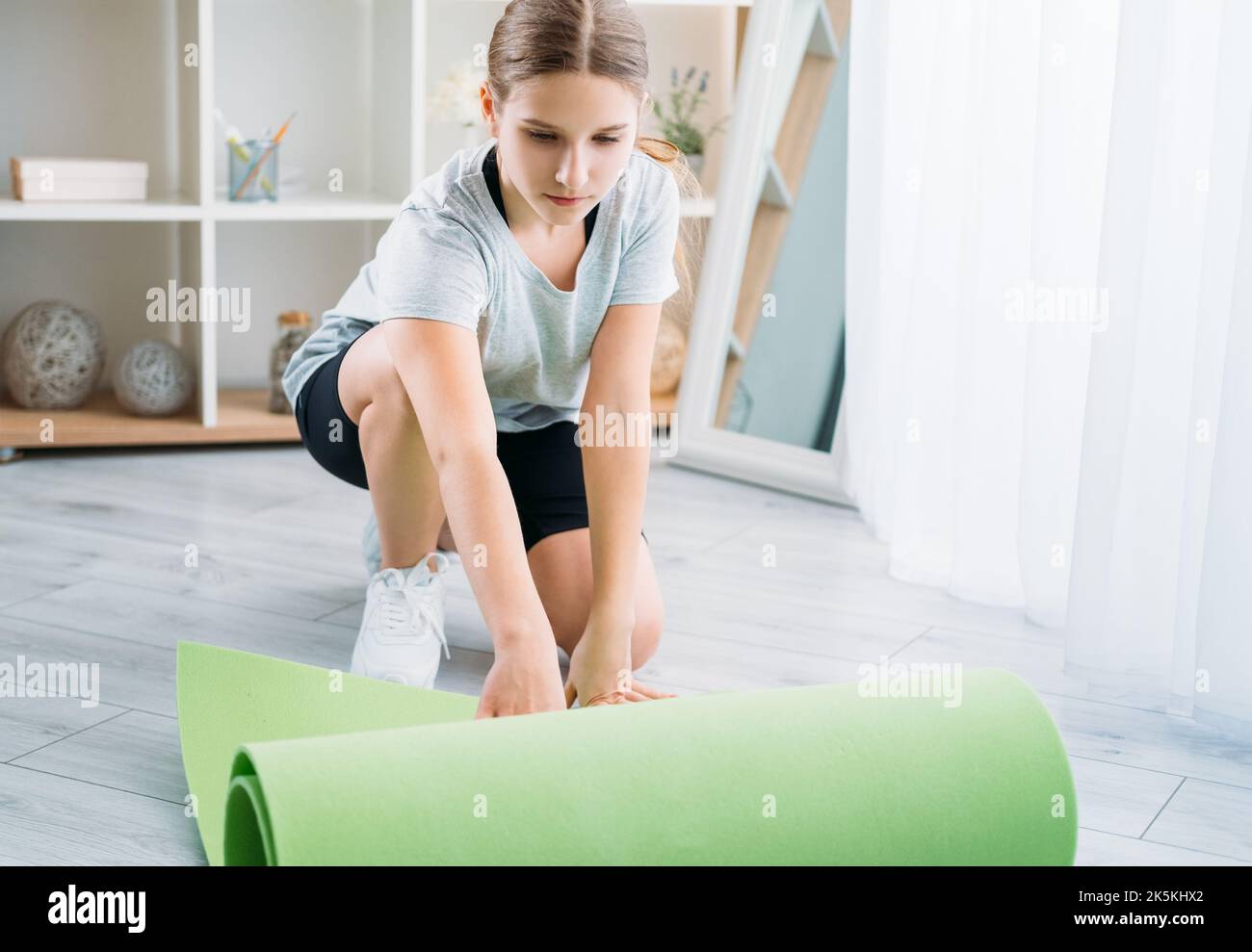 active kids home pilates girl unrolling yoga mat Stock Photo - Alamy