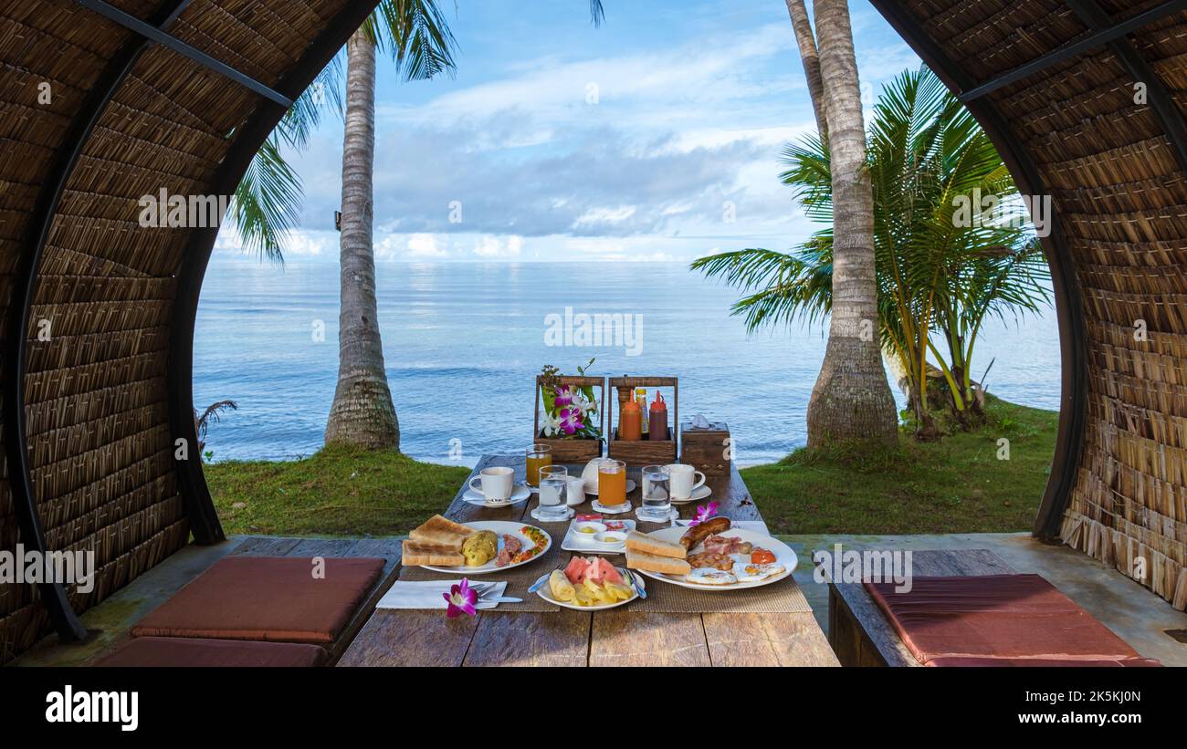 breakfast table on the beach with palm trees in Thailand. colorful ...