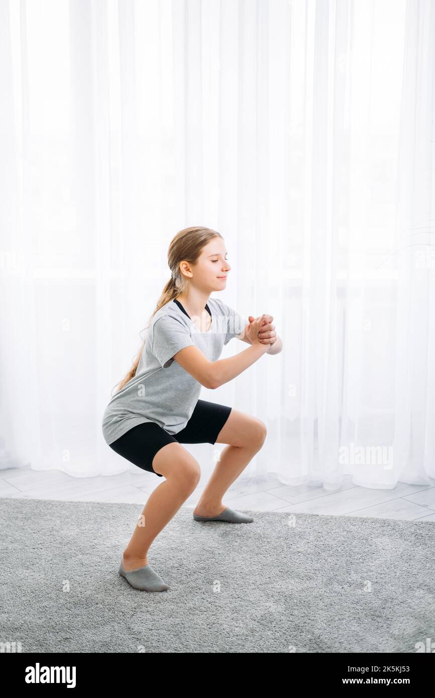 home fitness active kids girl doing squat exercise Stock Photo - Alamy