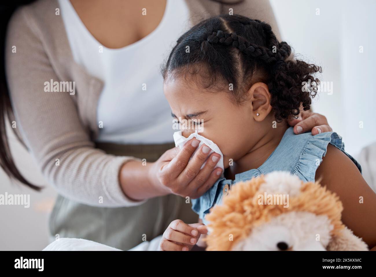 Mother clean sick child nose with tissue, playing with toy or teddy ...