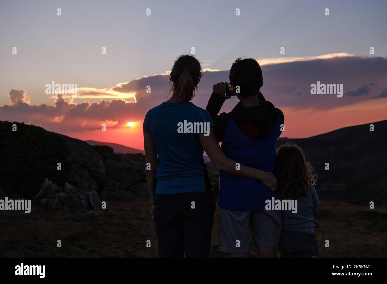 Mother with their sons watching the sunset Stock Photo - Alamy