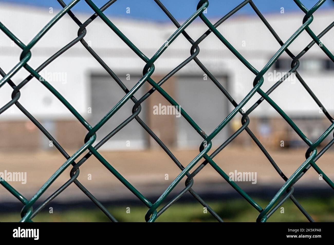 View through chain link fencing to defocussed factory building Stock ...