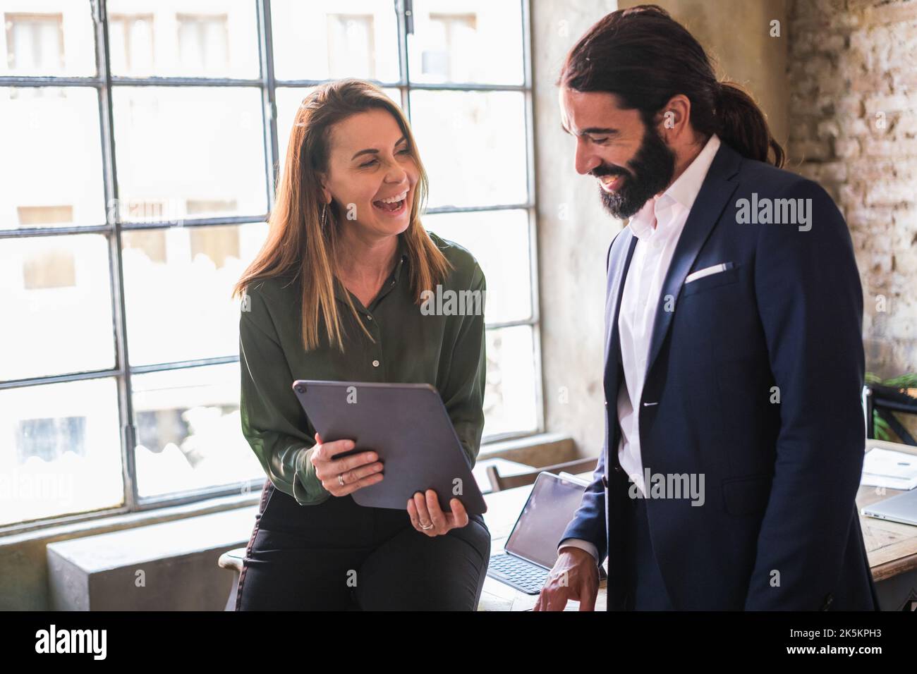 Two young co-workers sharing tasks together through the tablet Stock ...