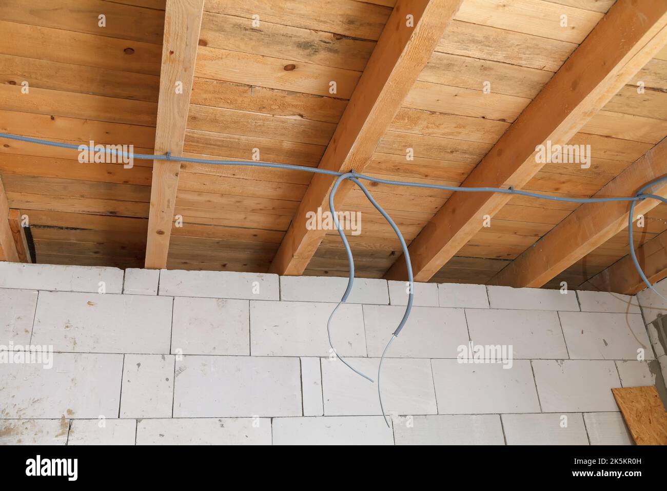 Electric wiring on a wooden ceiling overlap. Electrician in a ...