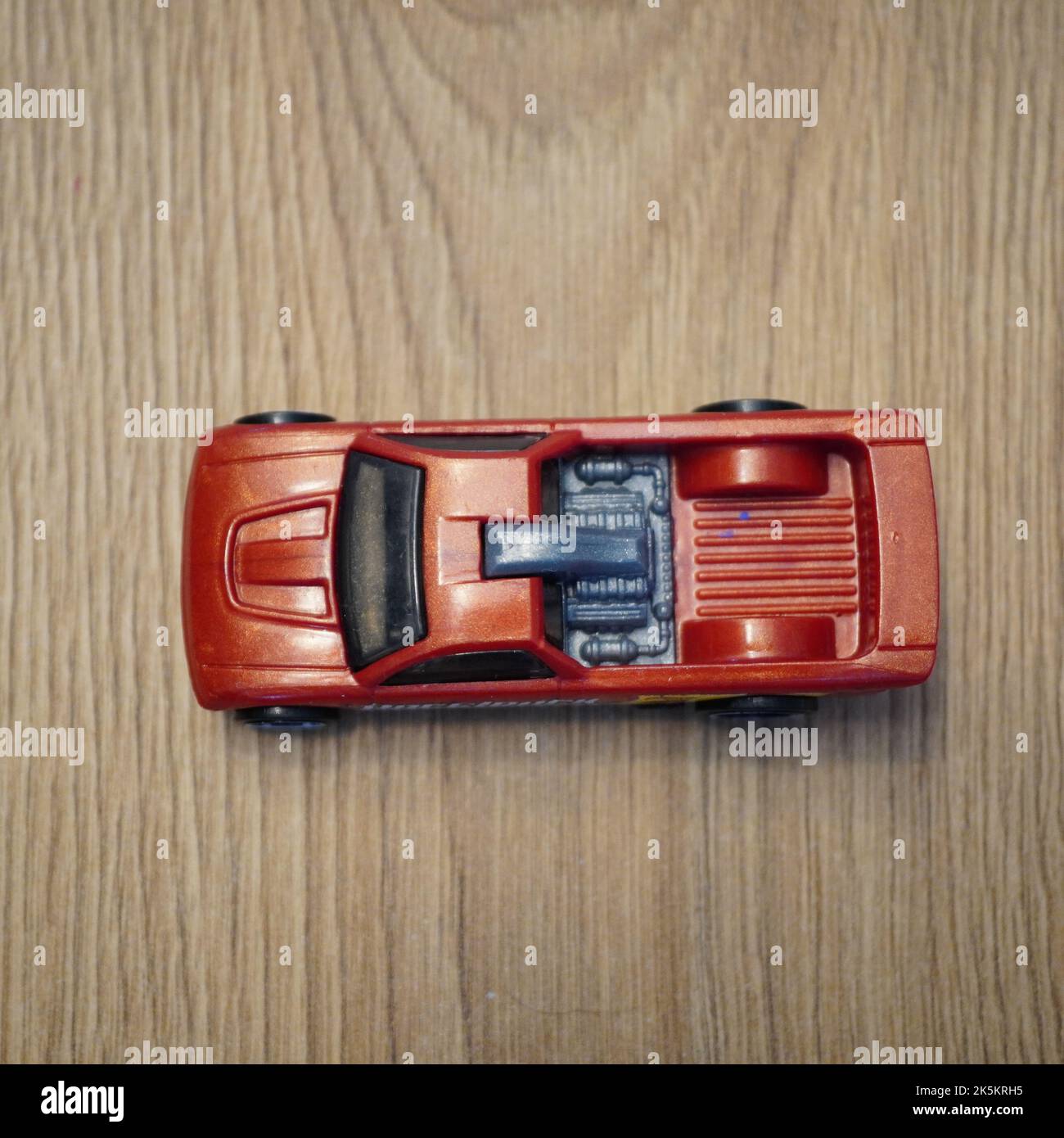 The top view of a red Mattel Hot Wheels toy car on a wooden surface ...