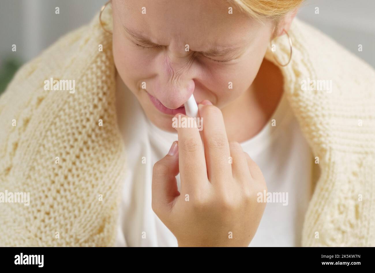 A girl with a cold treats a runny nose with a nasal spray. Medicine and ...