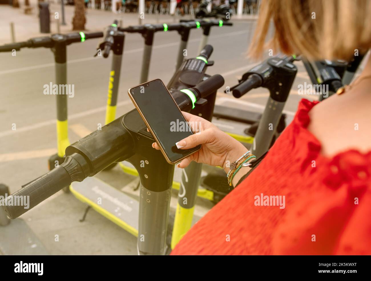 A woman's hand scans with a mobile phone the QR code of a scooter Stock ...