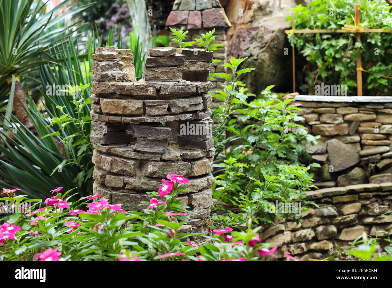 Decorative tower and stone wall, elements of landscape design and pink ...