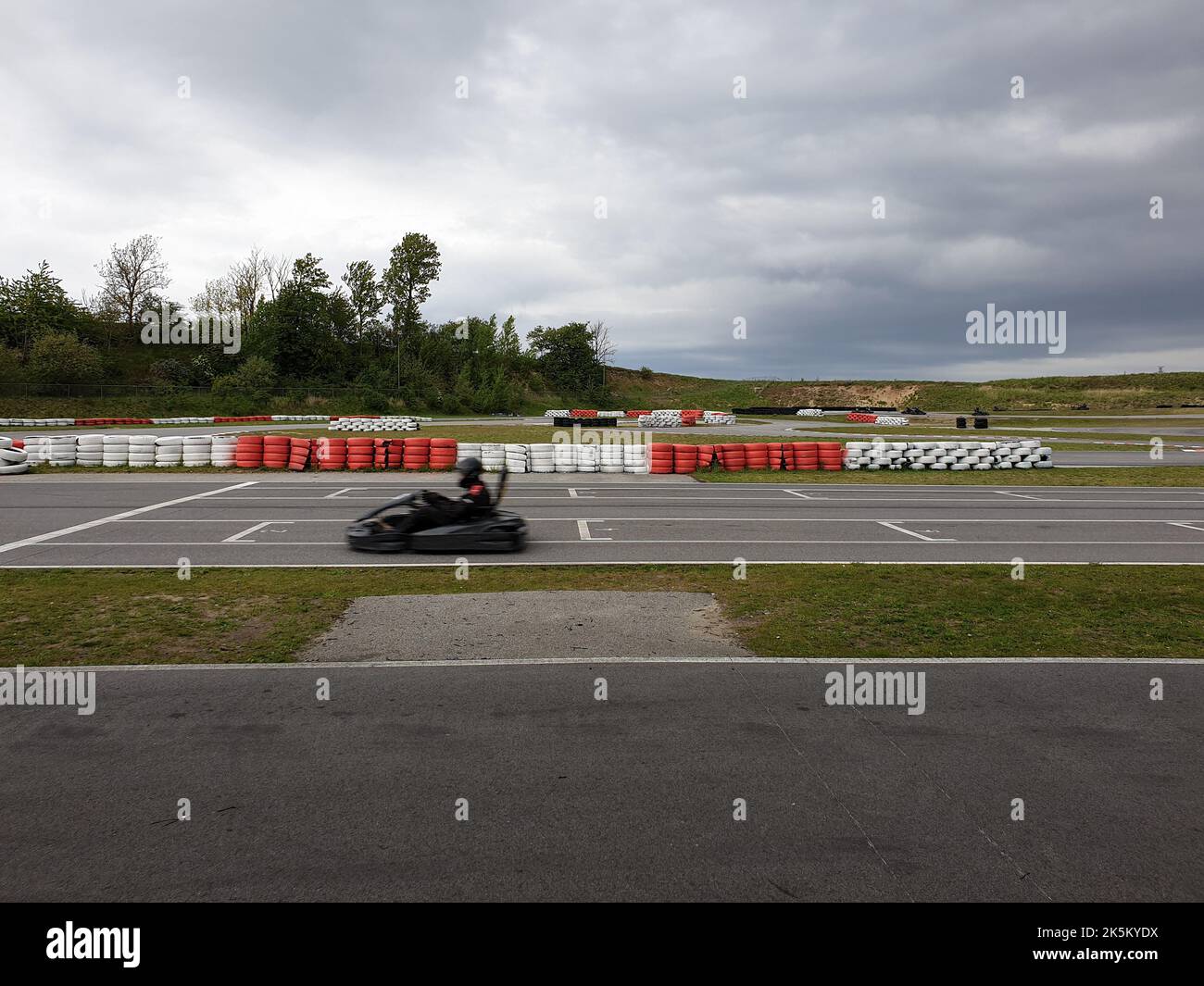 Boy driving go cart car around outdoor racing track in high speed on ...