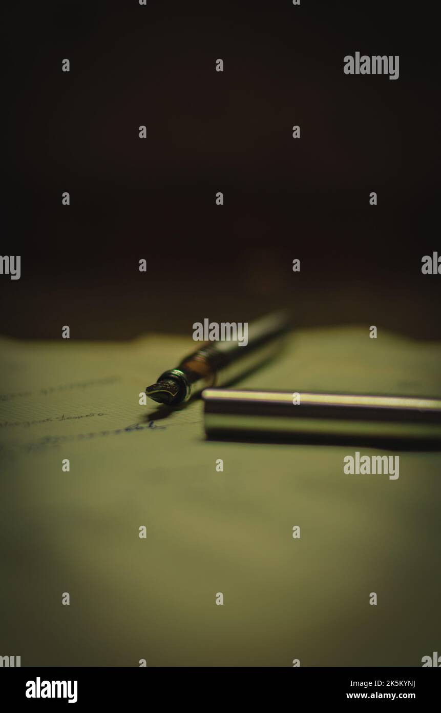 The vertical view of a silver fountain pen over the handwritten paper ...