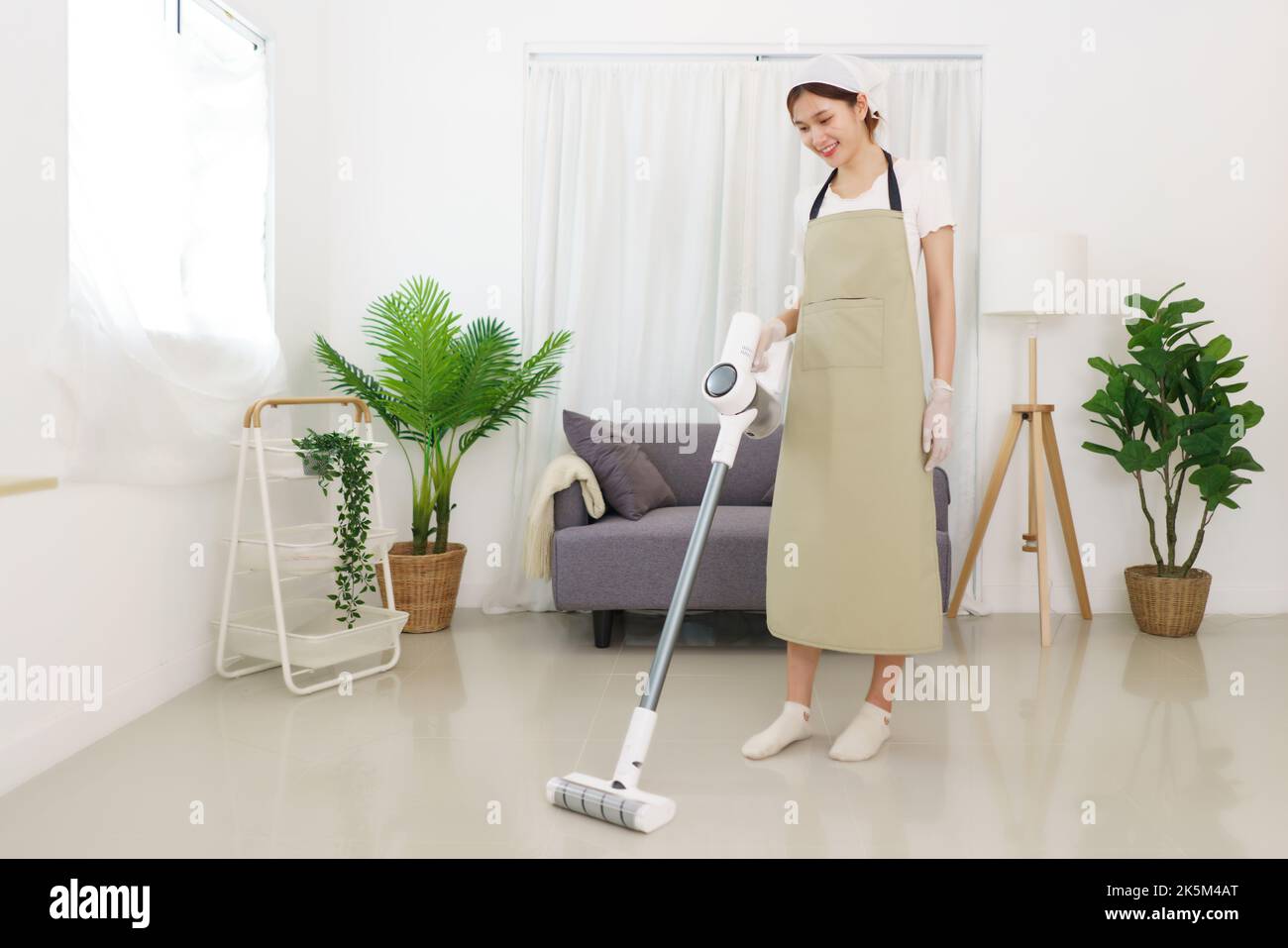 Lifestyle in living room concept, Young Asian woman using vacuum ...