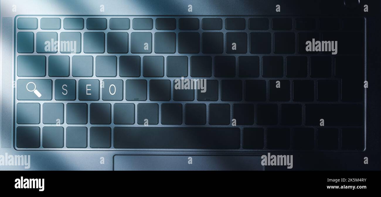 Laptop keyboard with blue light and SEO text on buttons. SEO Search ...