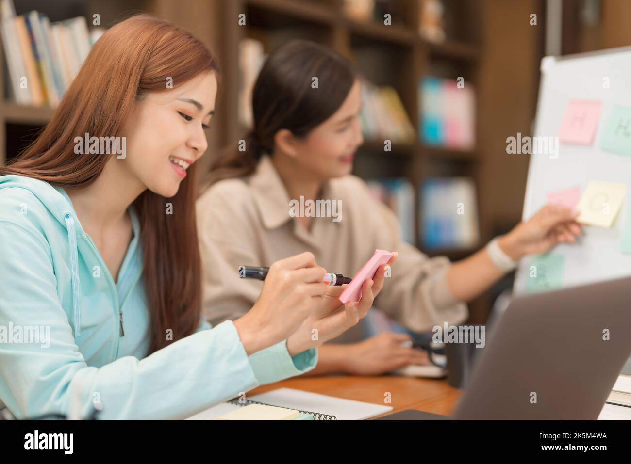 College education concept, Teenage girl is writing vocabulary on sticky ...