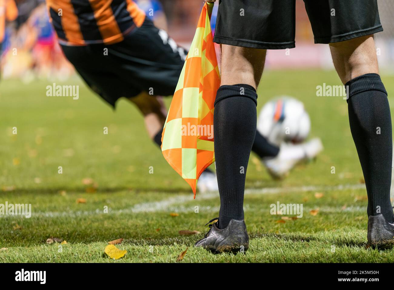 Footballer takes the corner. Detail of referee's legs during soccer ...