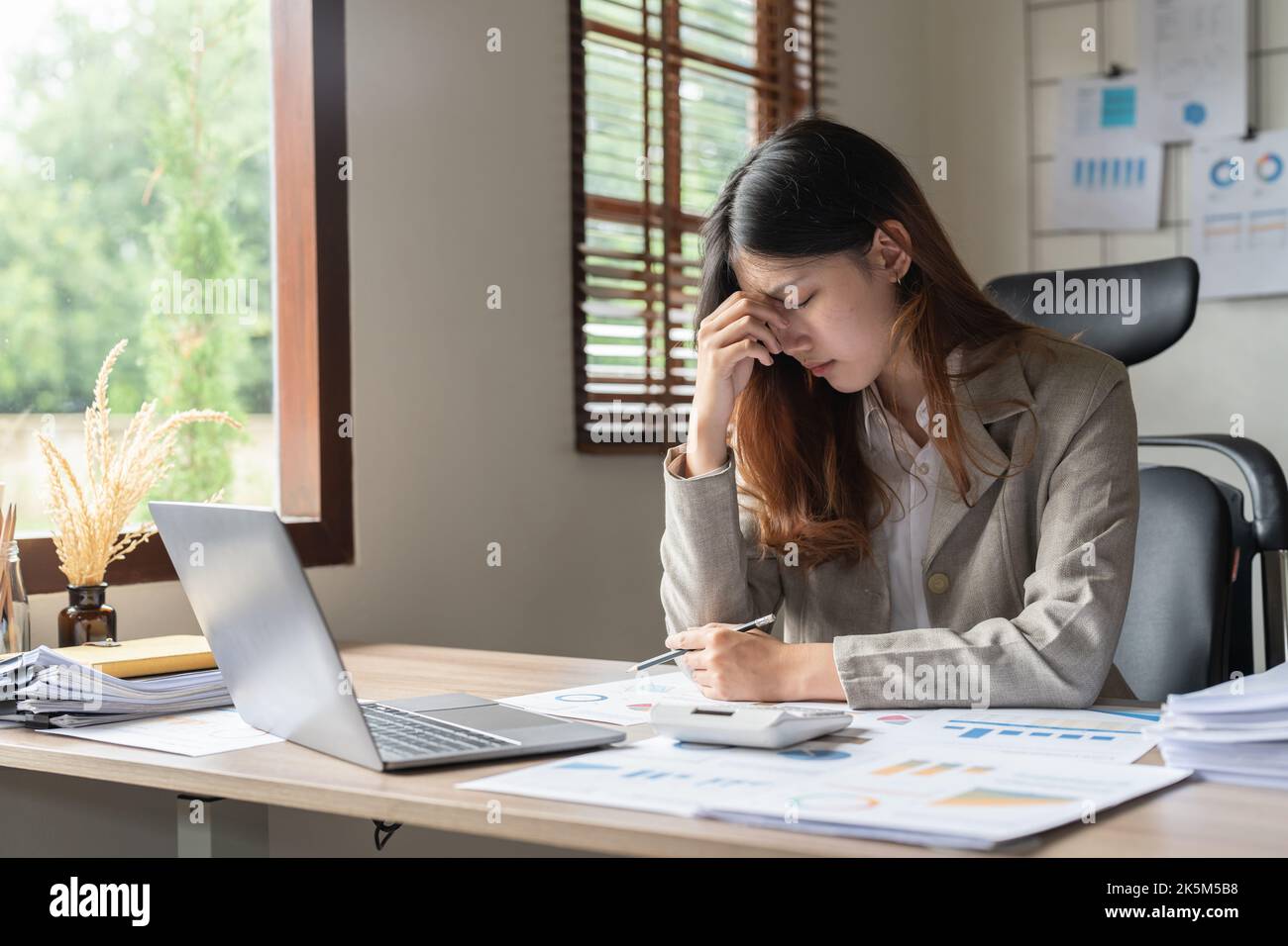 Upset woman touching head using calculator and laptop for calculating ...