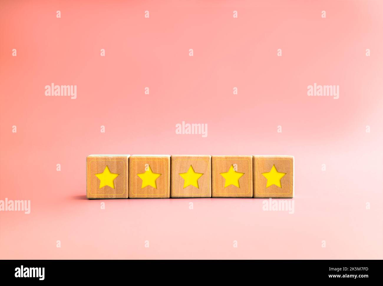Client feedback survey with yellow star on five wooden cube blocks on pastel pink background ...