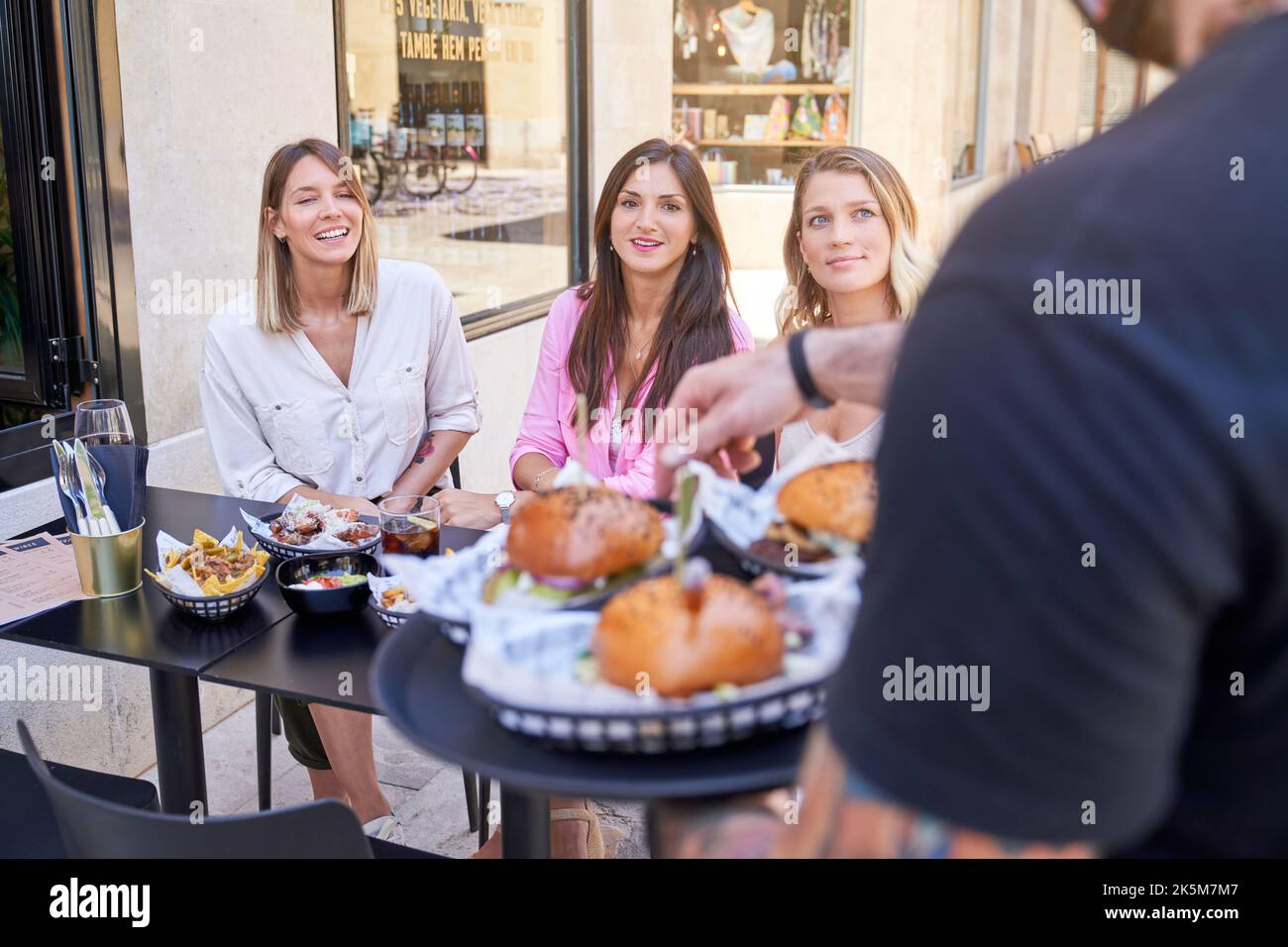 Waiter serving fast food for women in street cafe Stock Photo - Alamy