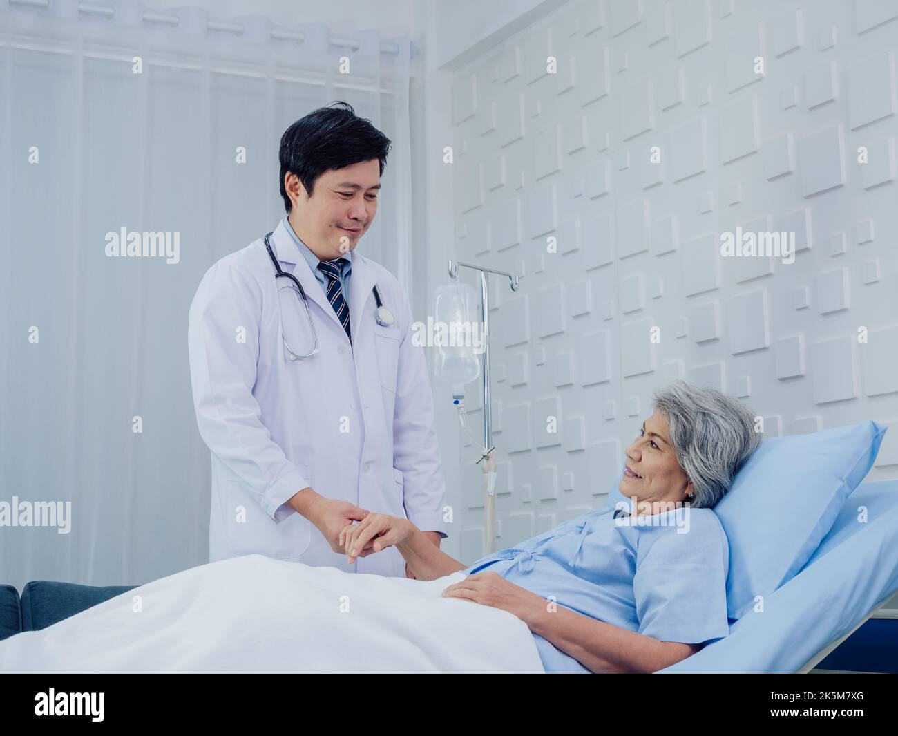 The kind Asian male doctor in white suit visits, talks and gives ...