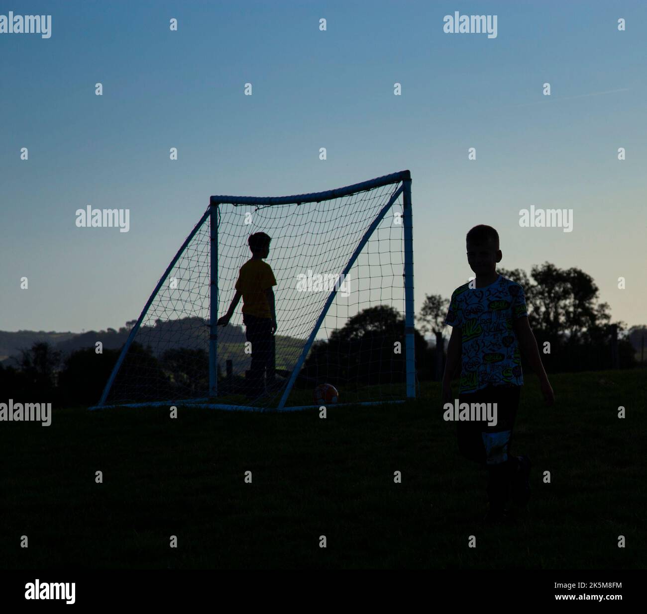 Boys playing football soccer as light fails and evening falls Stock ...