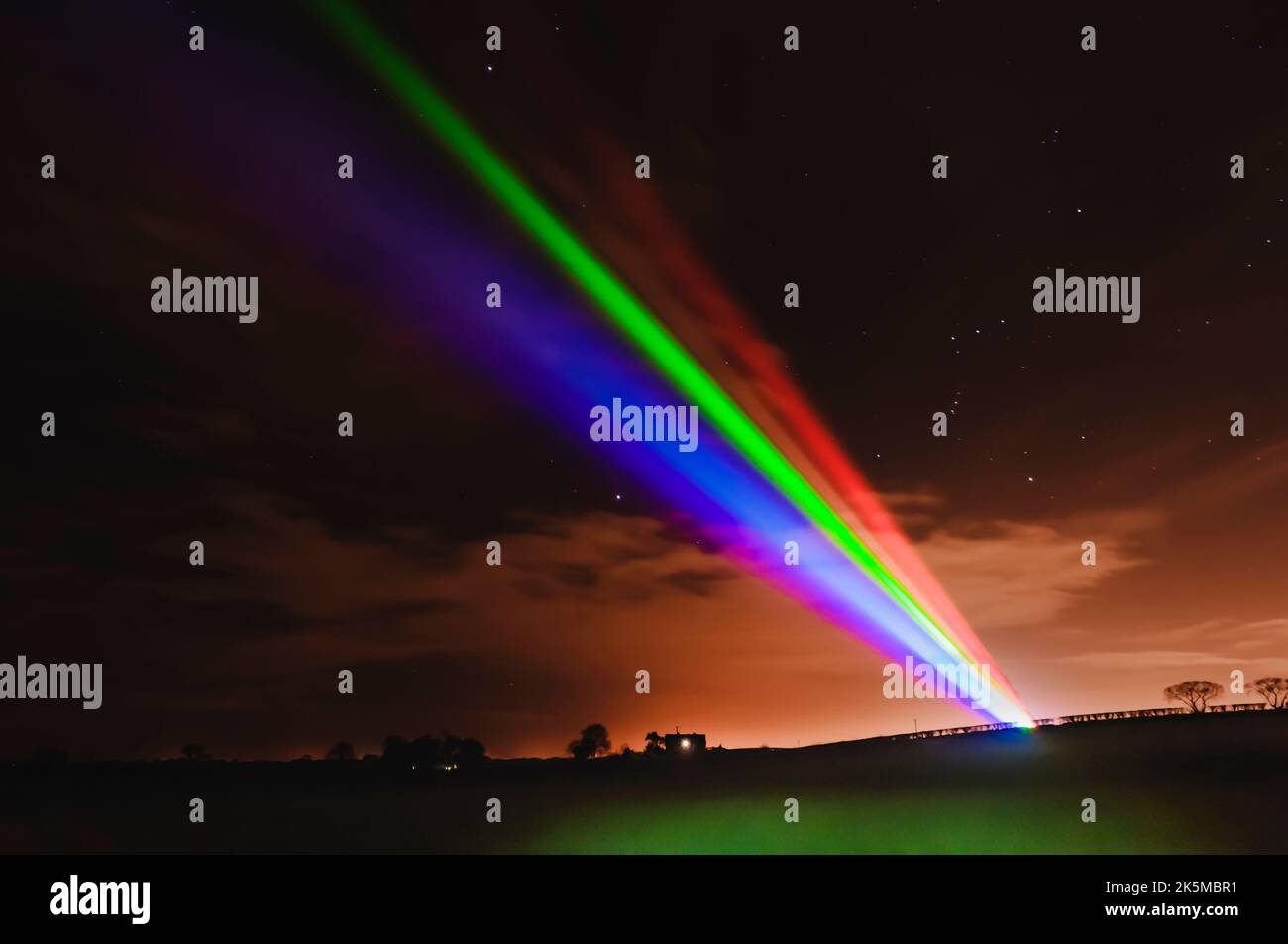 Rainbow coloured lasers shine across the night sky Stock Photo - Alamy
