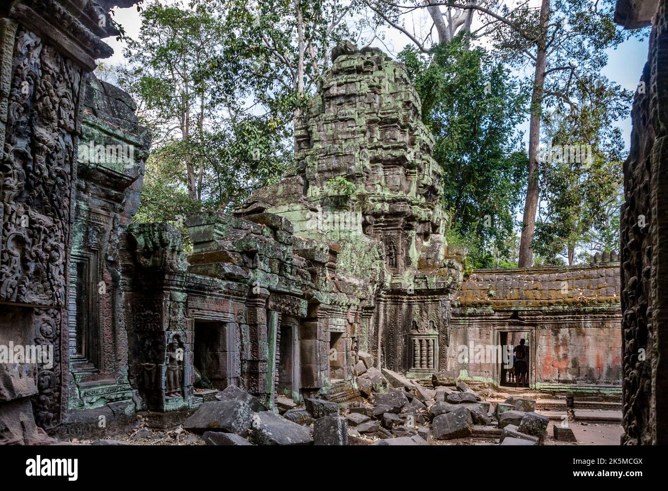 Inside Angkor Temple Ta Prohm with a tower and surrounded by buildings ...