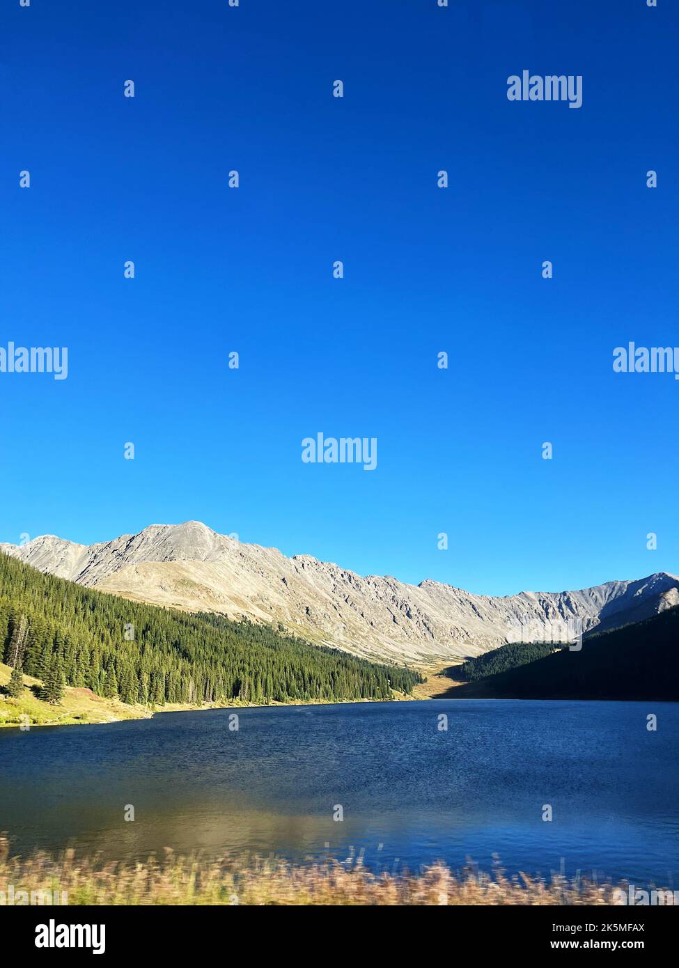 A vertical scenery of a blue lake surrounded by rocky mountains in ...