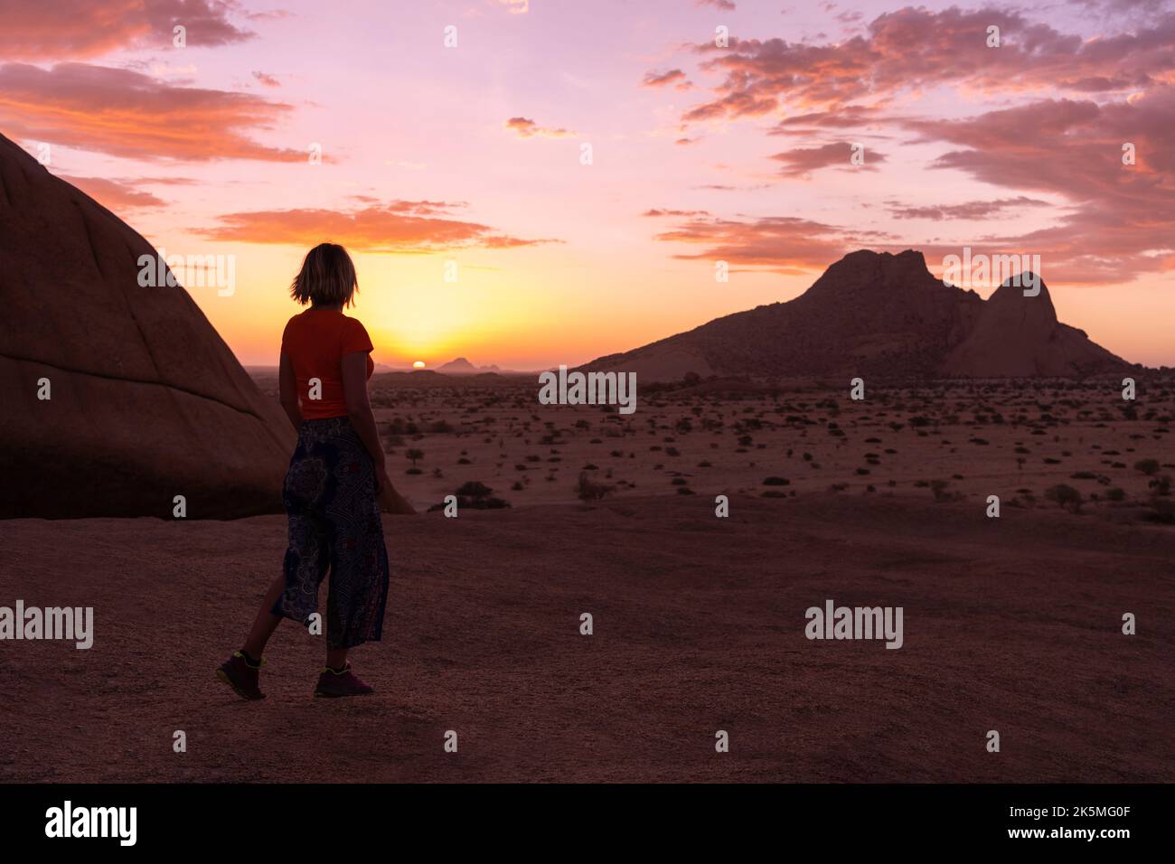 A woman walking towards the sunset in the Namibian desert Stock Photo ...