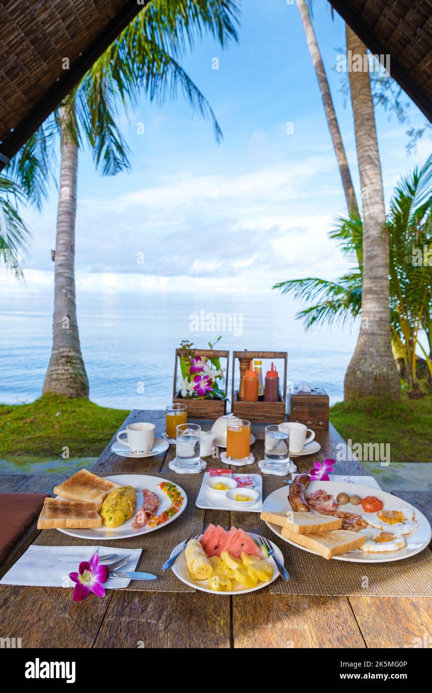 breakfast table on the beach with palm trees in Thailand. colorful ...