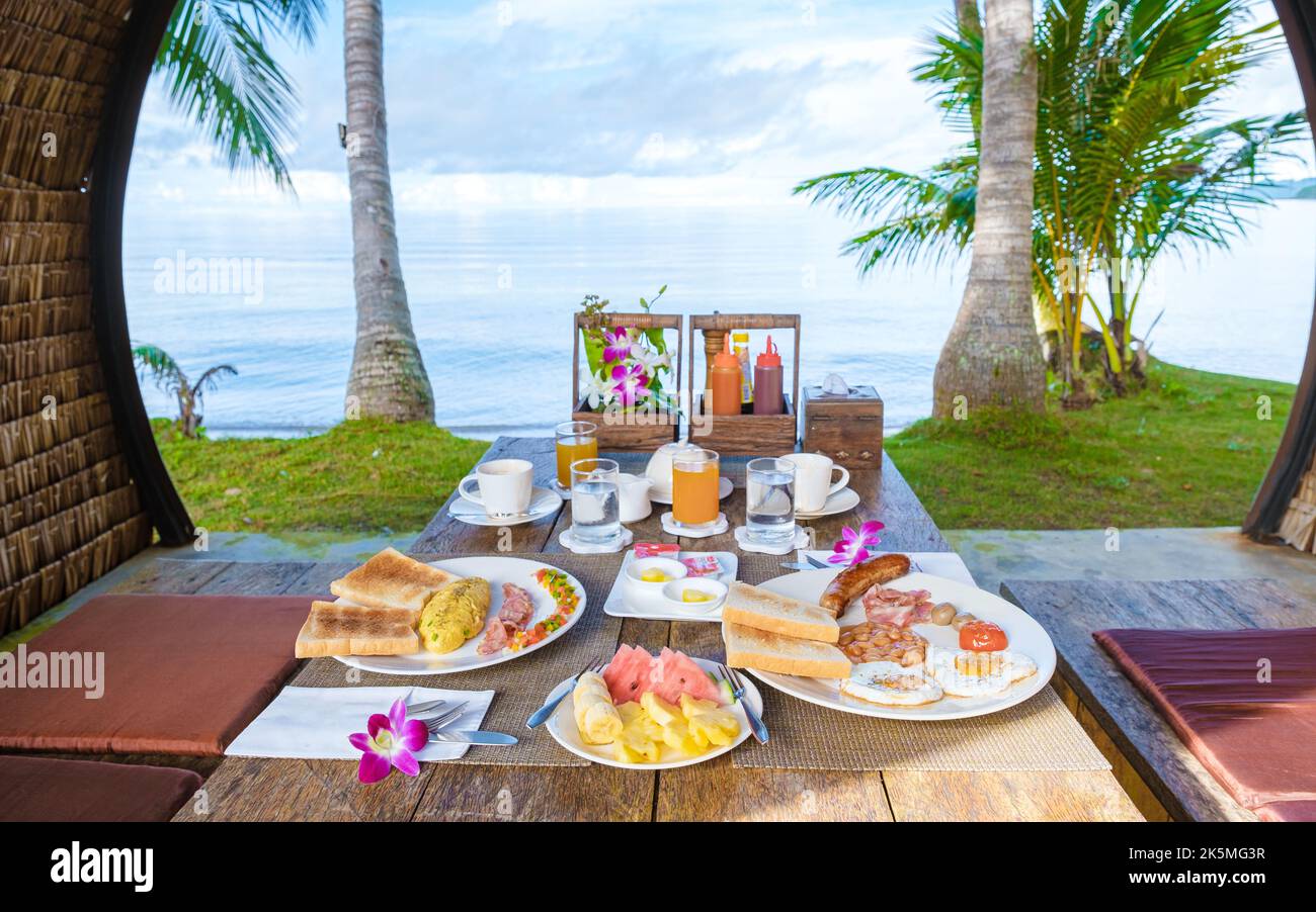 breakfast table on the beach with palm trees in Thailand. colorful ...