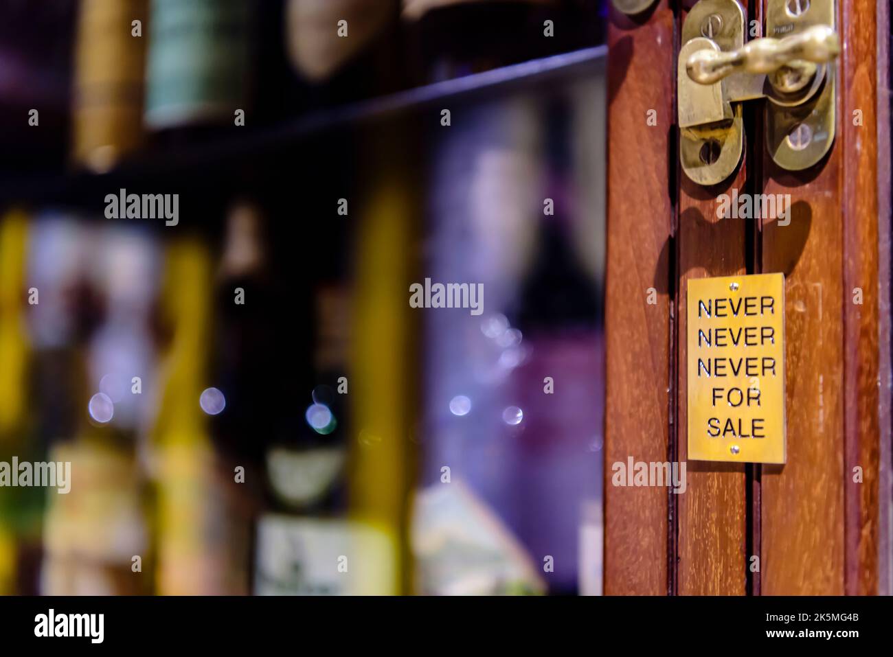 Sign on a display cabinet in a whiskey shop saying "Never, never, never ...