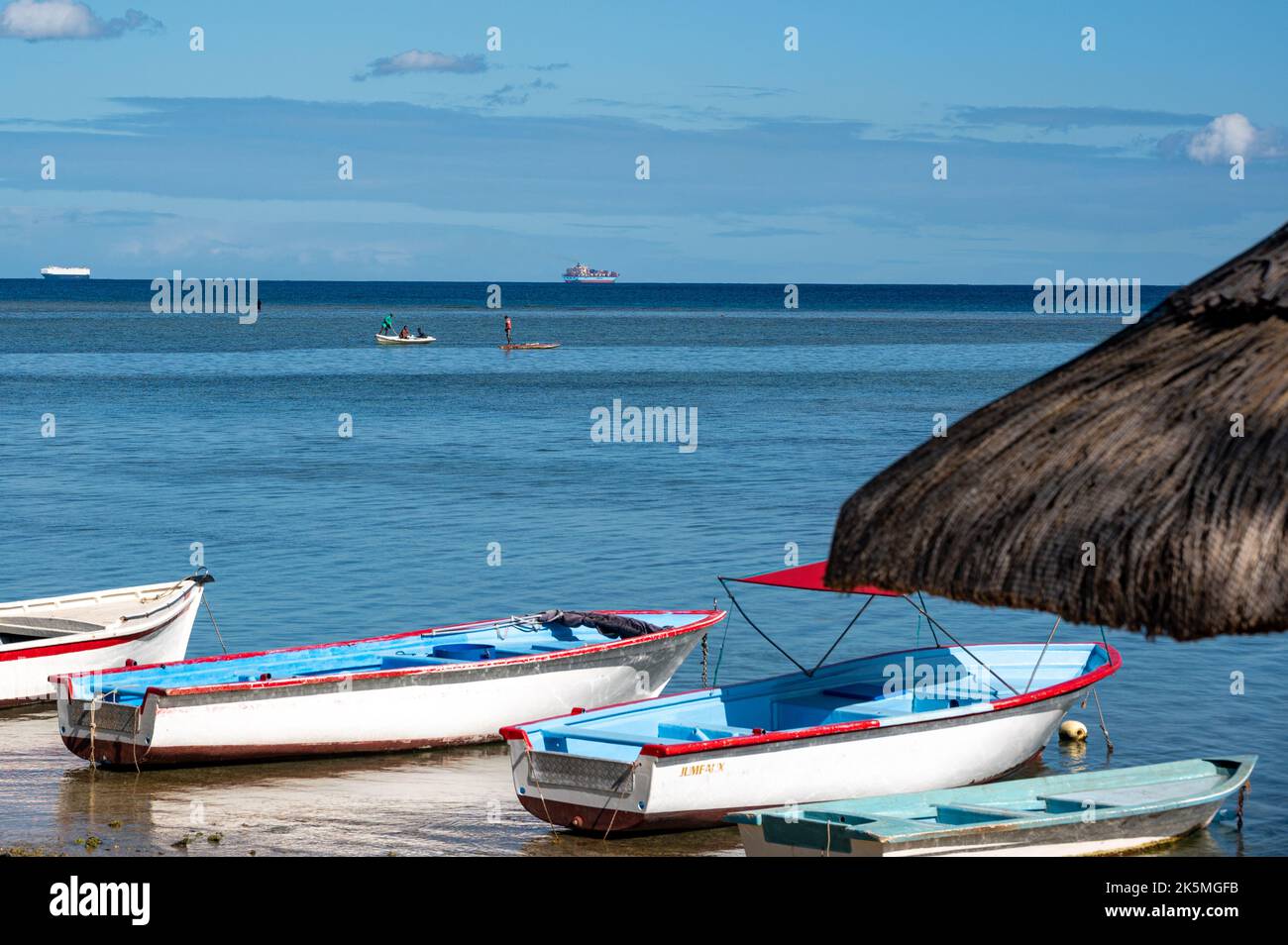 Fishermen in rowing boats with a large shipping tanker on the horizon ...
