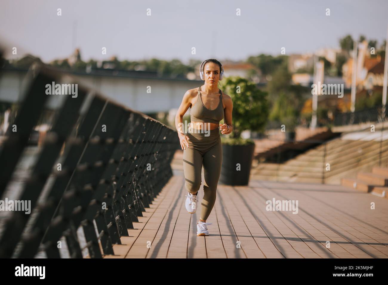 View at active young beautiful woman running on the promenade along the ...