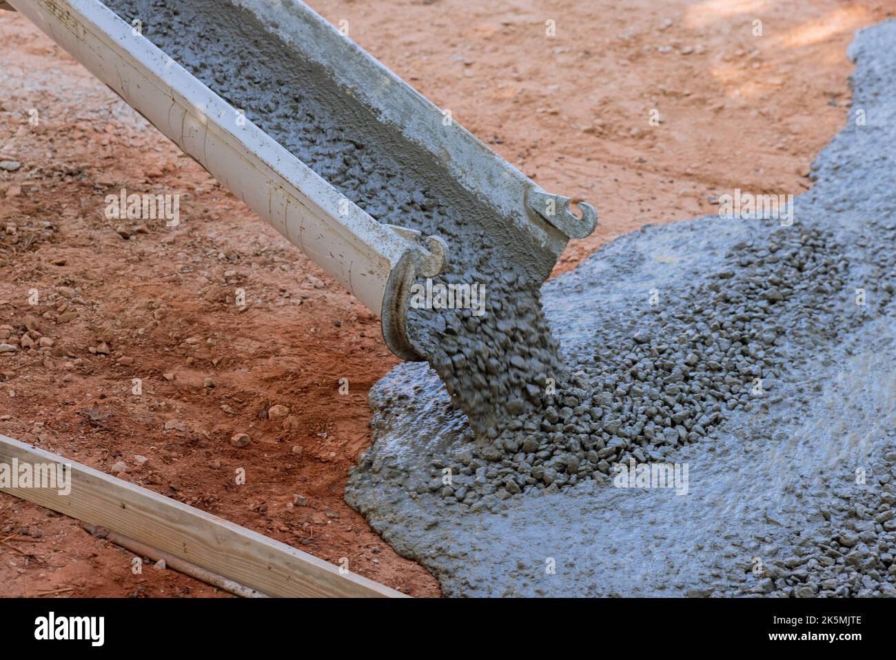 The concrete is being poured in course paving driveway at construction ...