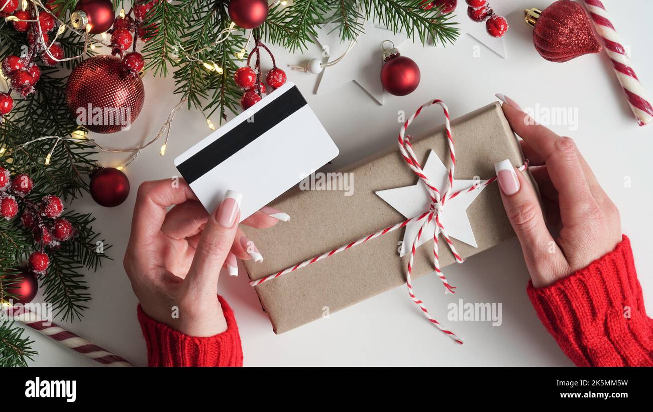Hands of woman in red sweater holding credit card and gift box on white ...