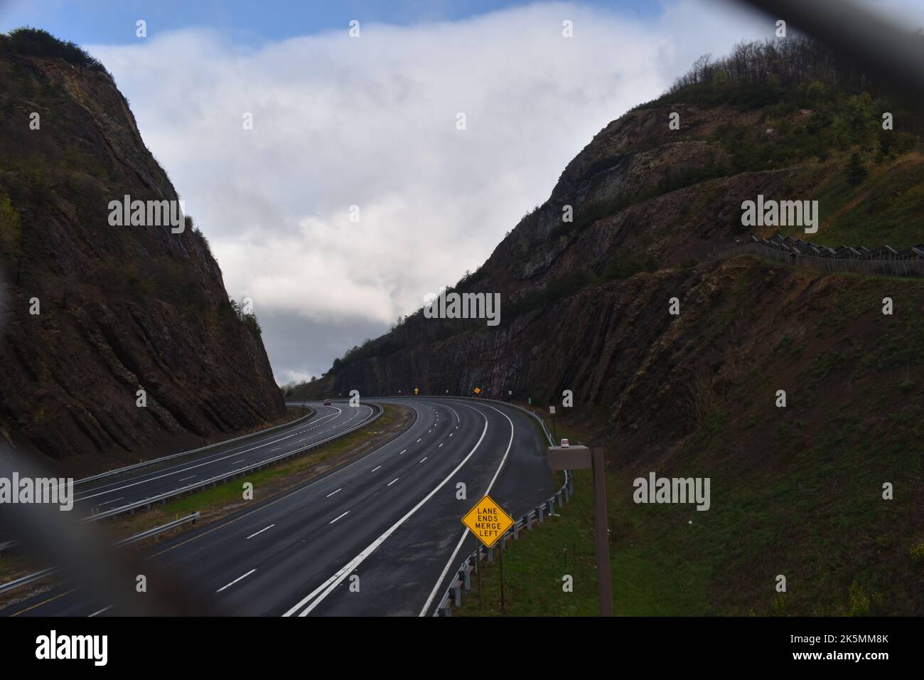 A curvy highway road through the green rocky hills with fluffy cloud in ...