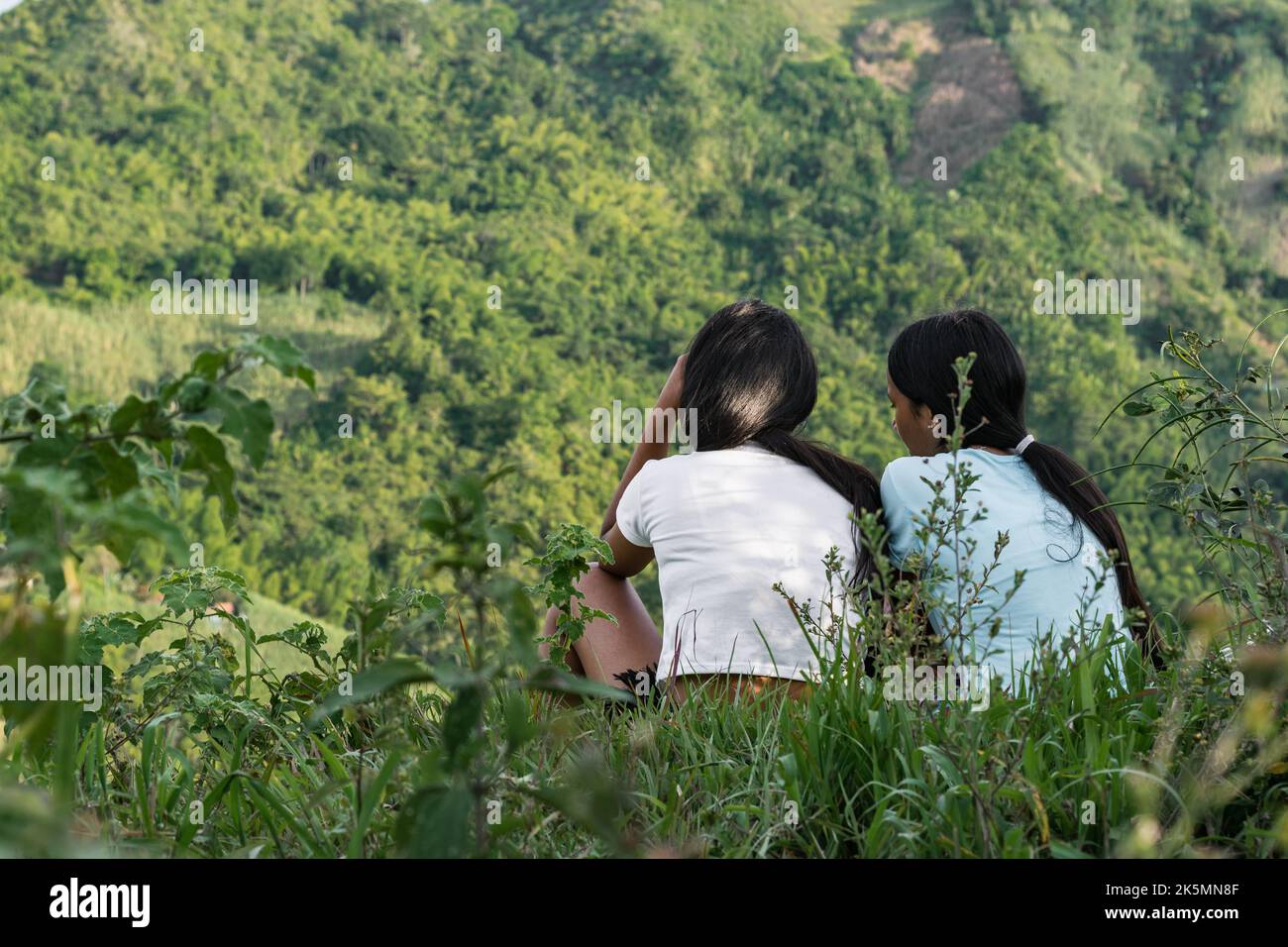 two brunette latina girls, on top of a mountain talking and watching ...