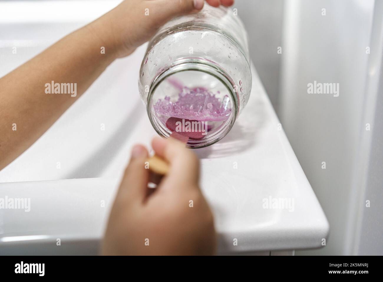 Chemical experiment on growing crystals. Child hands take out grown ...