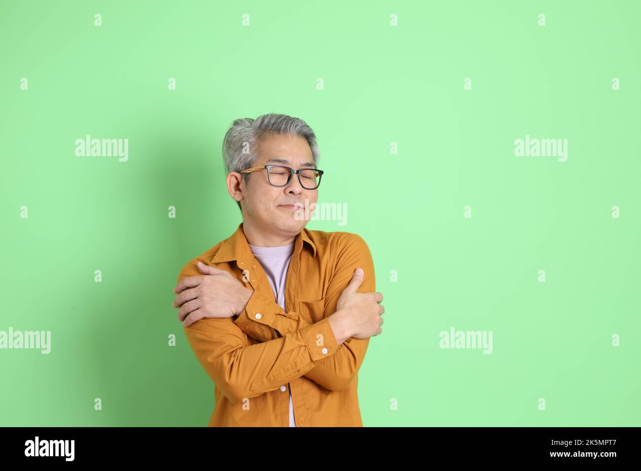 The 40s adult Asian man with yellow shirt standing on the green ...