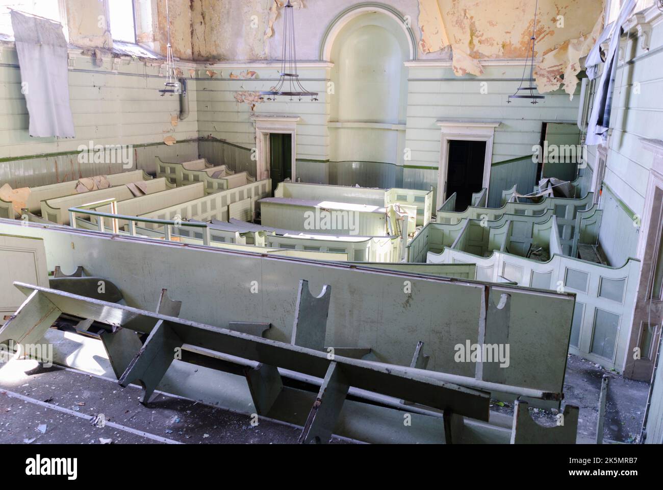 Derelict courtroom with broken benches and plaster falling off the ...