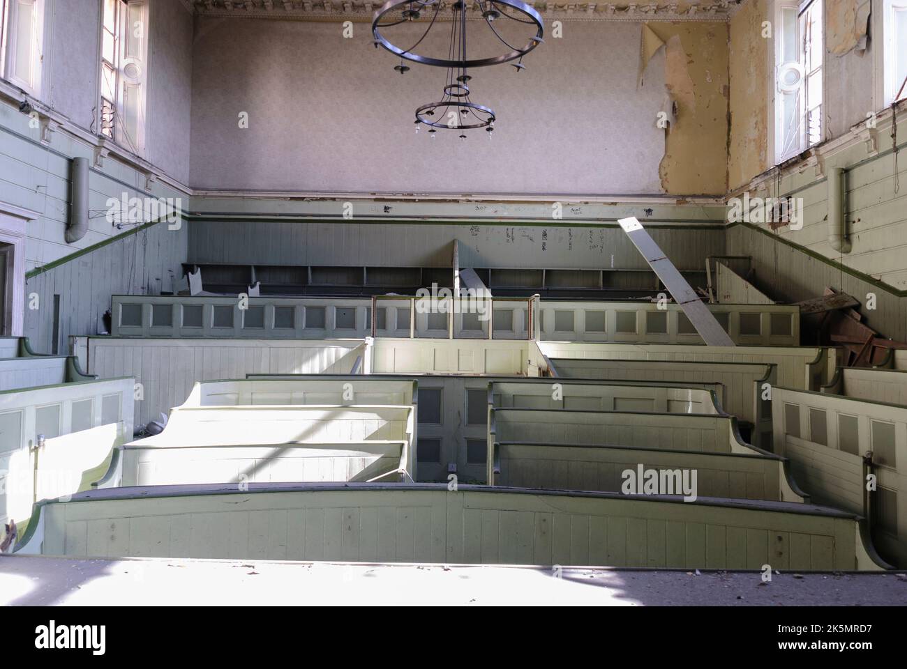 Derelict courtroom with broken benches and plaster falling off the ...