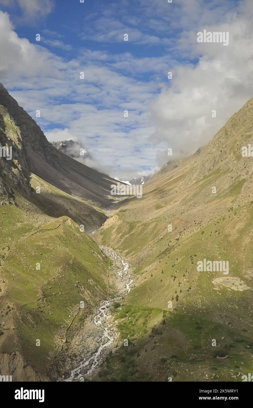 Dry mountains covered with clouds from peak, flowing water from top of ...